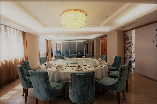 Uma sala de conferências com uma mesa redonda, cadeiras e um lustre.