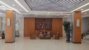 Lobby com balcão de recepção, área de estar e uma planta grande.