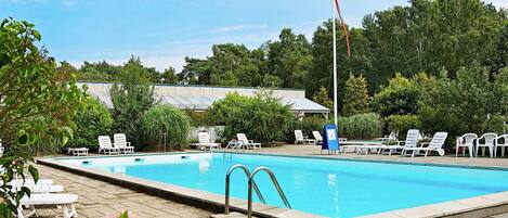 Piscina com espreguiçadeiras e mastro.