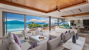 Uma sala de estar moderna com uma televisão grande, assentos confortáveis e vista para uma piscina e montanhas.
