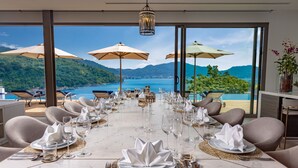Mesa de jantar posta para refeição, com vista para um lago e montanhas.