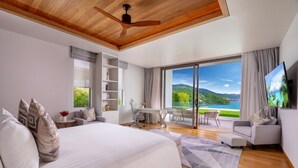 Quarto moderno com uma cama grande, uma escrivaninha e uma televisão. Possui varanda com vista para as montanhas e para o mar.