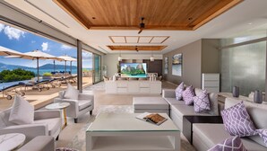 Uma sala de estar moderna com uma televisão grande, assentos confortáveis e vista para o exterior.
