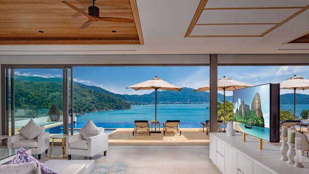 Sala de estar moderna com uma grande parede de vidro com vista para um lago montanhoso e paisagístico.