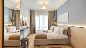 Quarto de hotel moderno com uma cama grande, uma escrivaninha e vista para a cidade pela janela.