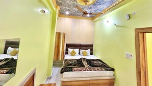 Quarto de hotel pequeno com uma cama, um ventilador de teto e um ponto de luz.