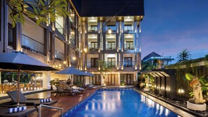 Um hotel com piscina, área de estar externa e fachada bem iluminada.