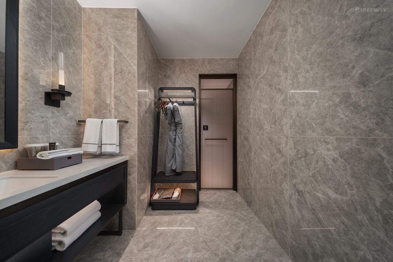 Um banheiro moderno com piso de mármore, toucador preto com espelho e porta-toalhas.