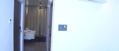 Quarto de hotel com cama, mesa de cabeceira, ar condicionado, controle remoto e tomada na parede.