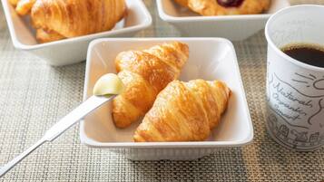 Uma mesa com croissants e uma xícara de café.
