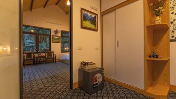 Quarto de hotel com piso estampado, um armário de madeira, um quadro emoldurado e uma estante com flores.
