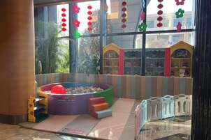 Espaço infantil com piscina de bolinhas, estruturas de recreação macias e vista para um edifício com fachada colorida.