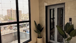 Um interior moderno com grandes janelas, um vaso de planta e uma porta com painéis de vidro.