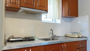 Cozinha com armários de madeira, pia de aço inoxidável e janela com cortinas.