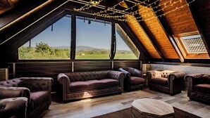 Quarto estilo loft com uma grande janela, sofás de couro e uma mesa de centro de madeira.