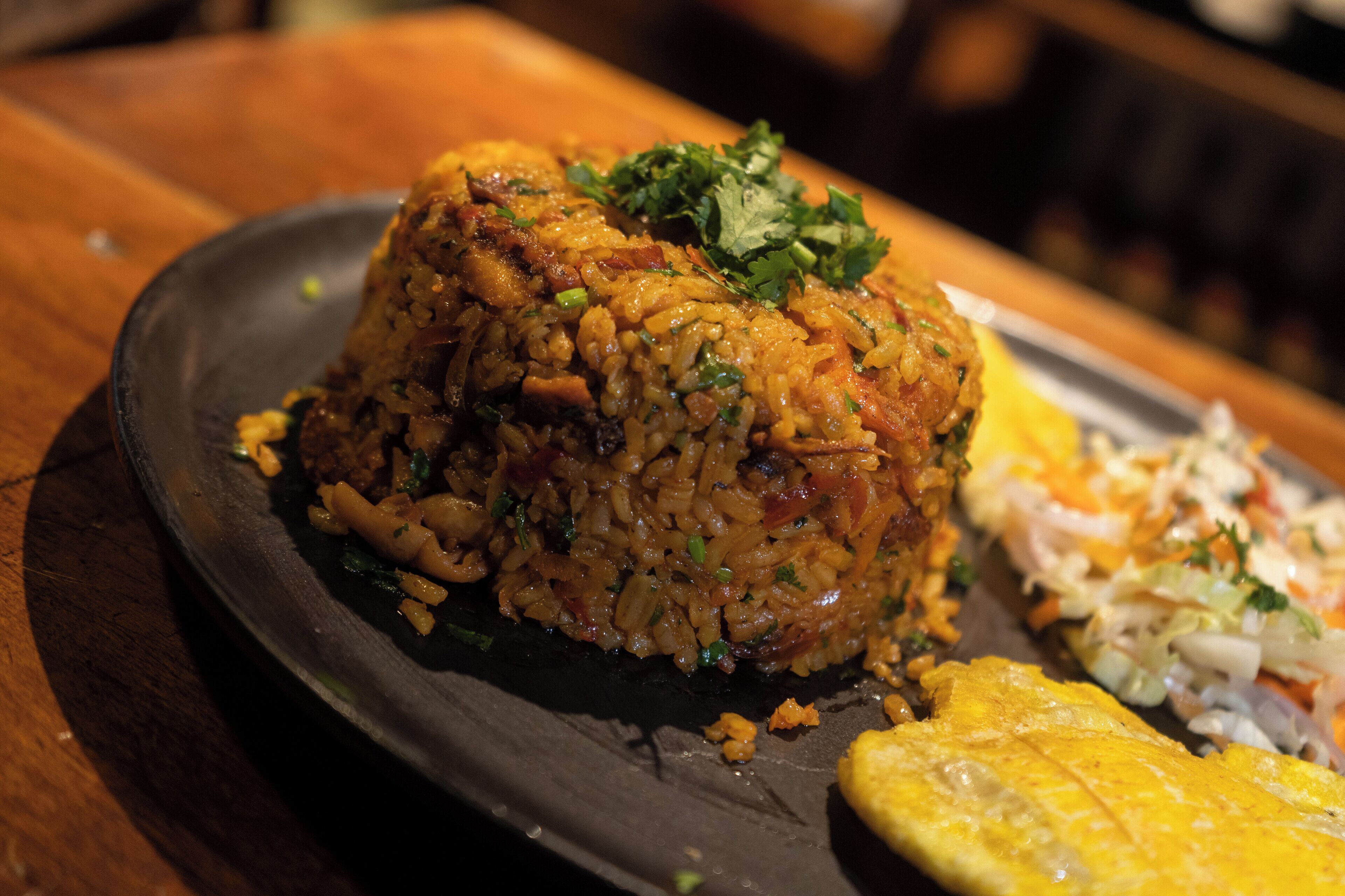 Prato de comida com arroz, legumes e um enfeite em um prato escuro.