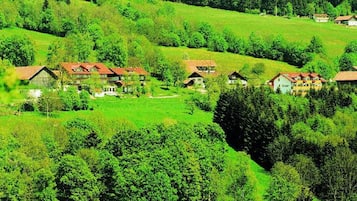 Paisagem rural com casas aninhadas entre campos verdes e árvores.
