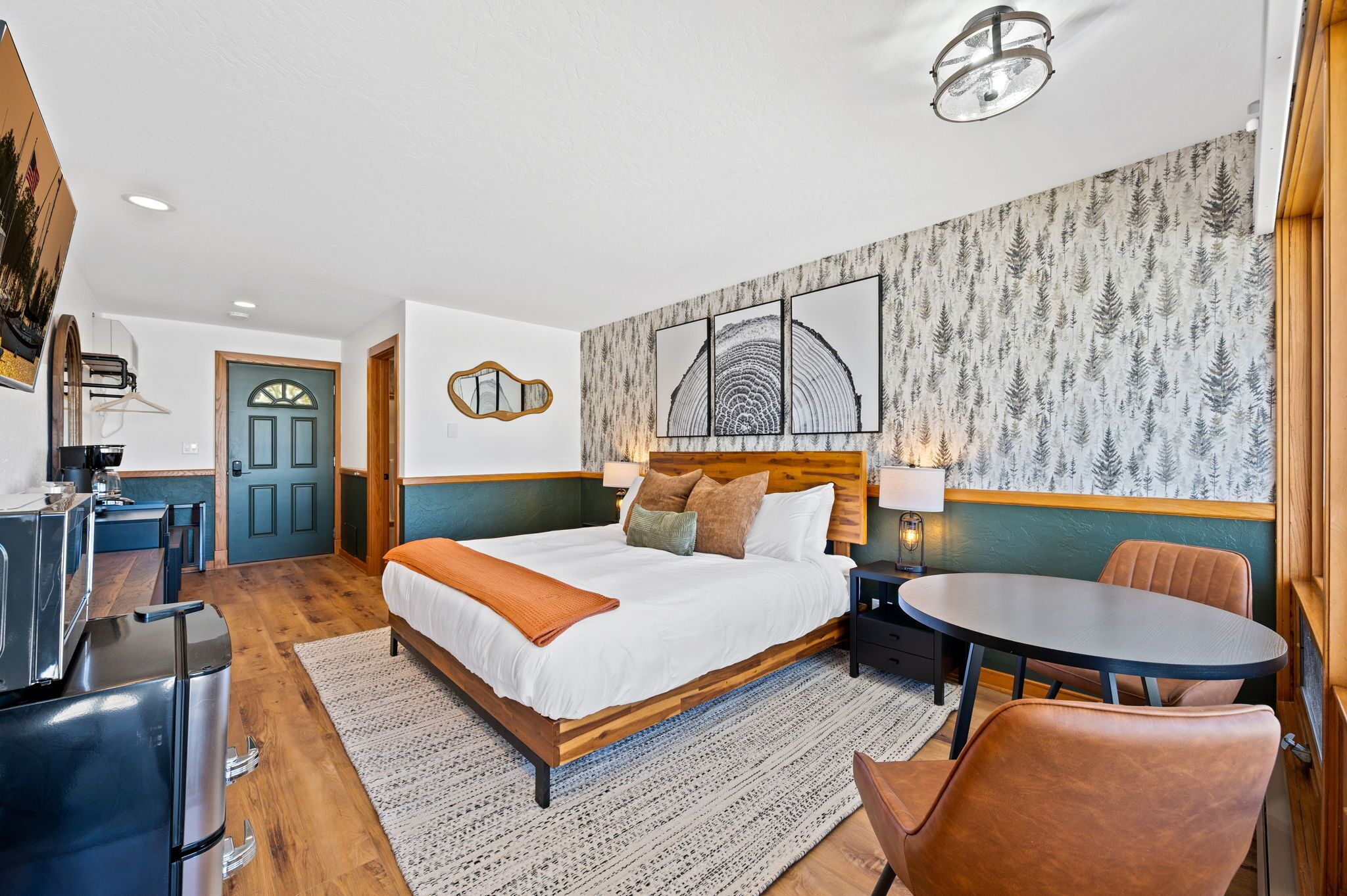 Quarto de hotel moderno com uma cama grande, uma escrivaninha e uma área de refeições.