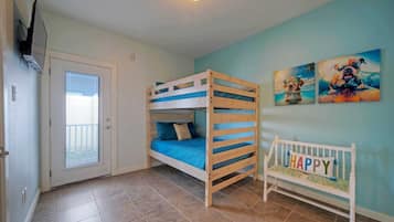 Um quarto com beliche, porta com vista e parede com dois quadros de cães.