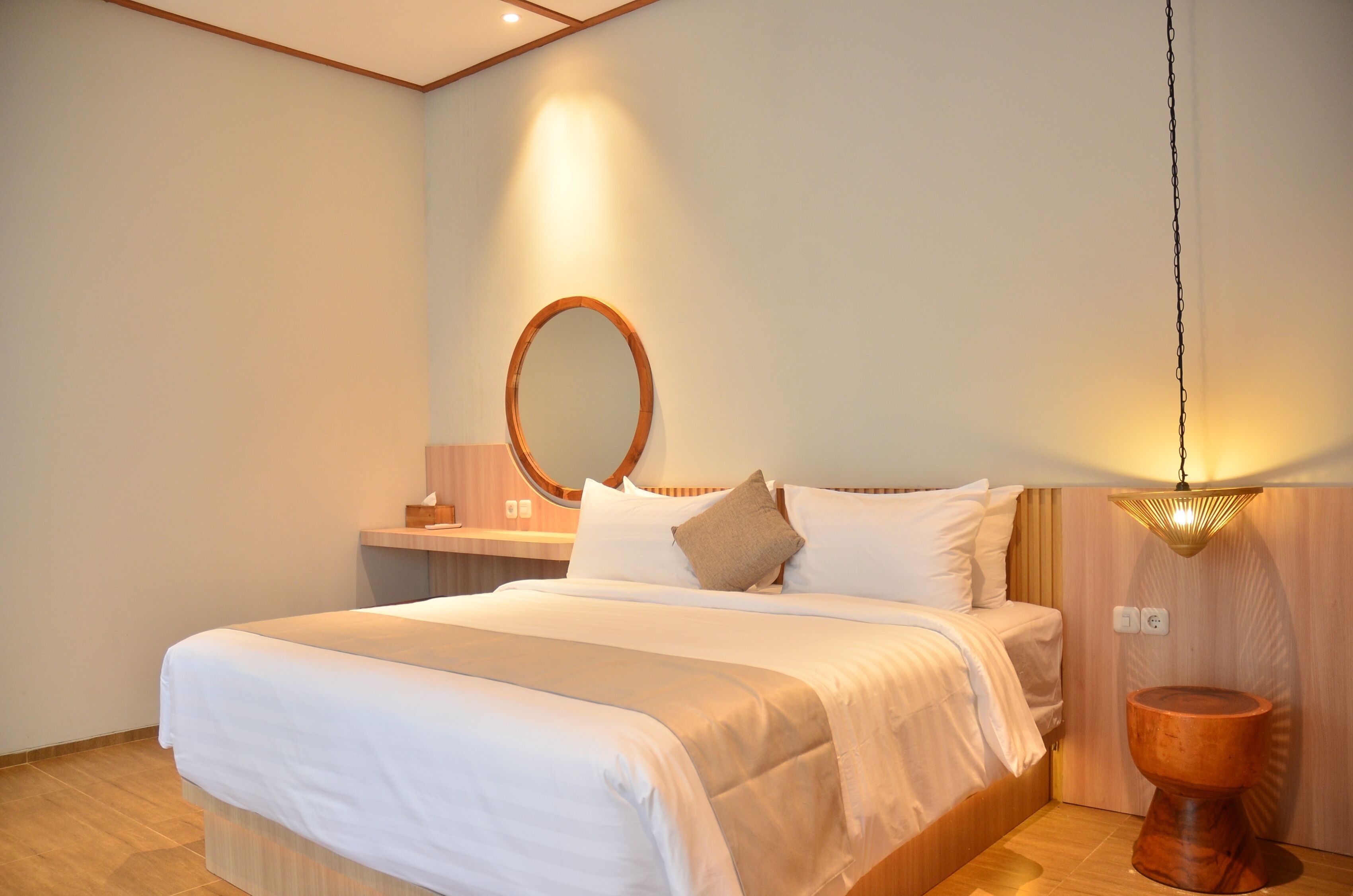 Um quarto moderno com uma cama grande, uma mesa de cabeceira de madeira, um espelho redondo e uma luminária de parede com design exclusivo.