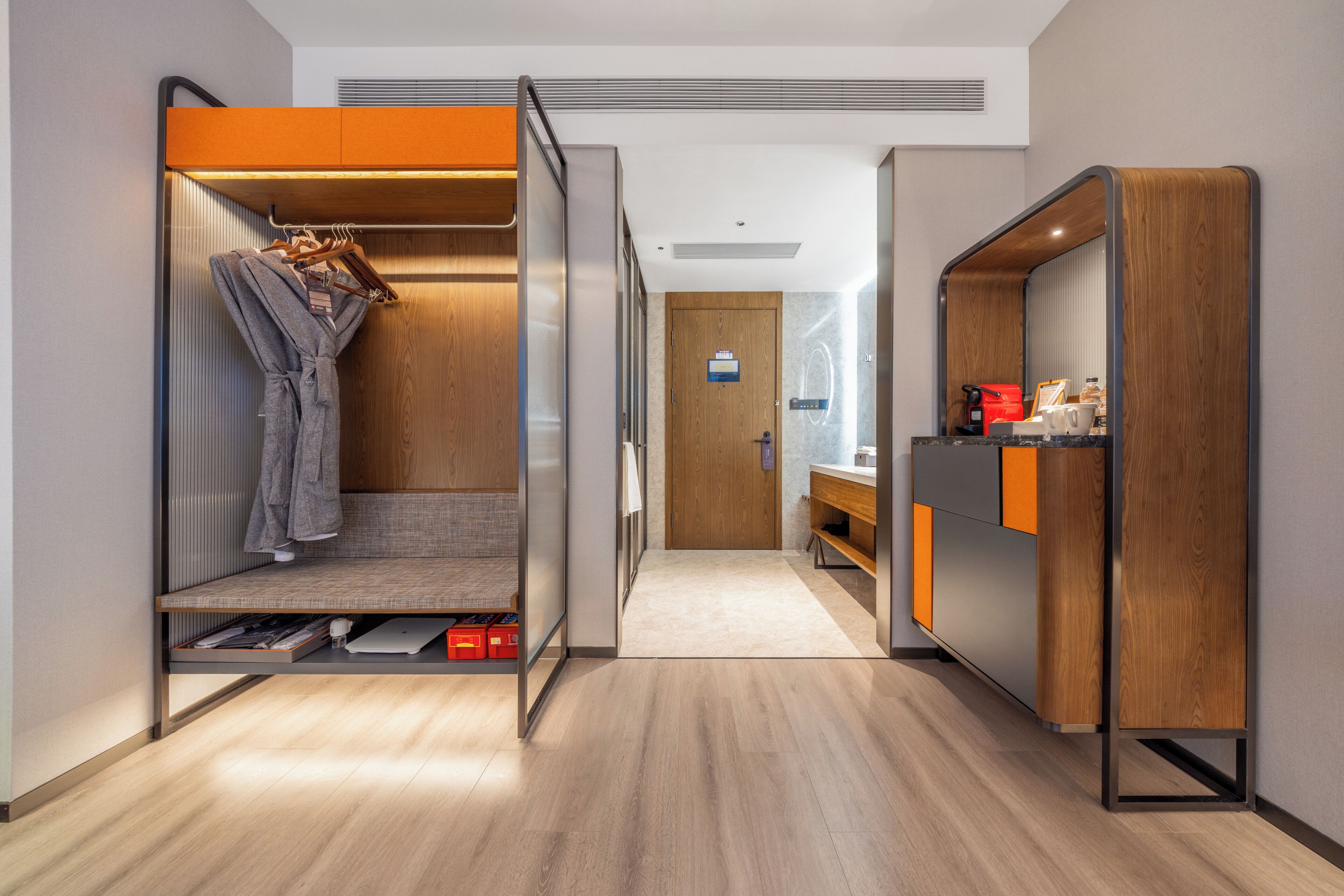 Quarto de hotel com closet espaçoso, cama, escrivaninha e banheiro.