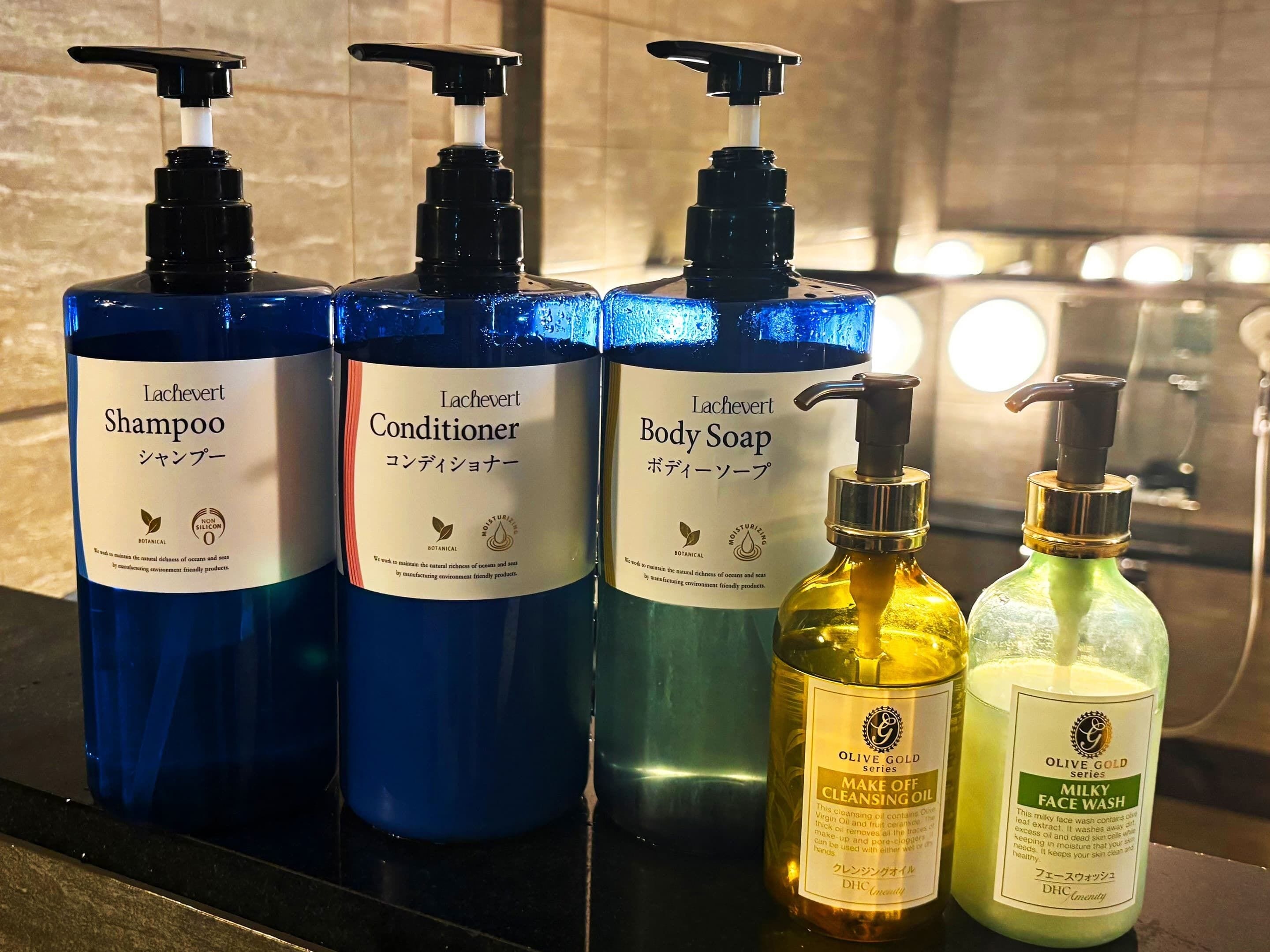 Quatro frascos de produtos de cuidados para a pele Lachevert e dois frascos de óleo de limpeza e sabonete facial da linha Olive Gold sobre um balcão.