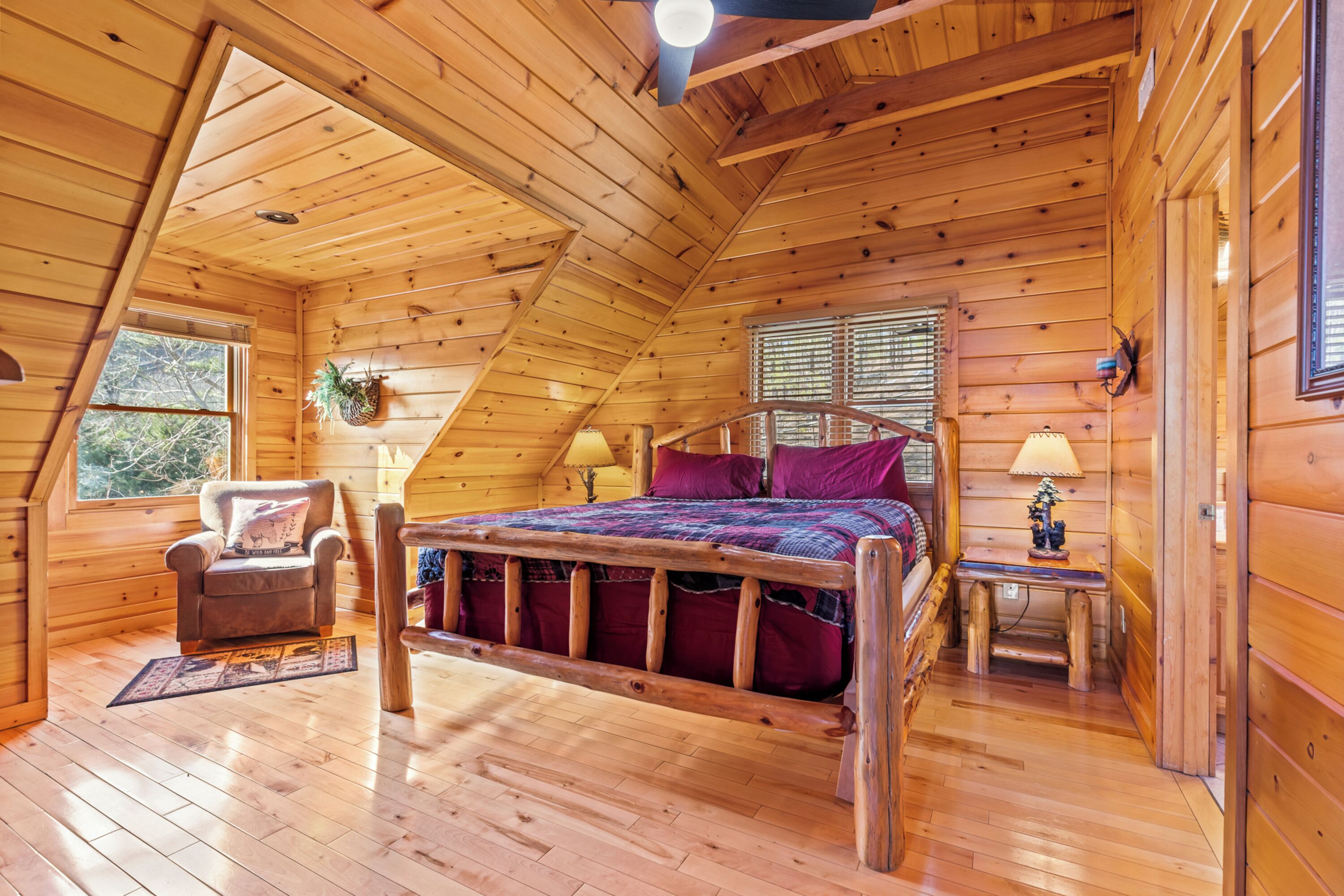 Quarto de cabana de madeira acolhedor, com uma cama, uma poltrona e uma mesinha.