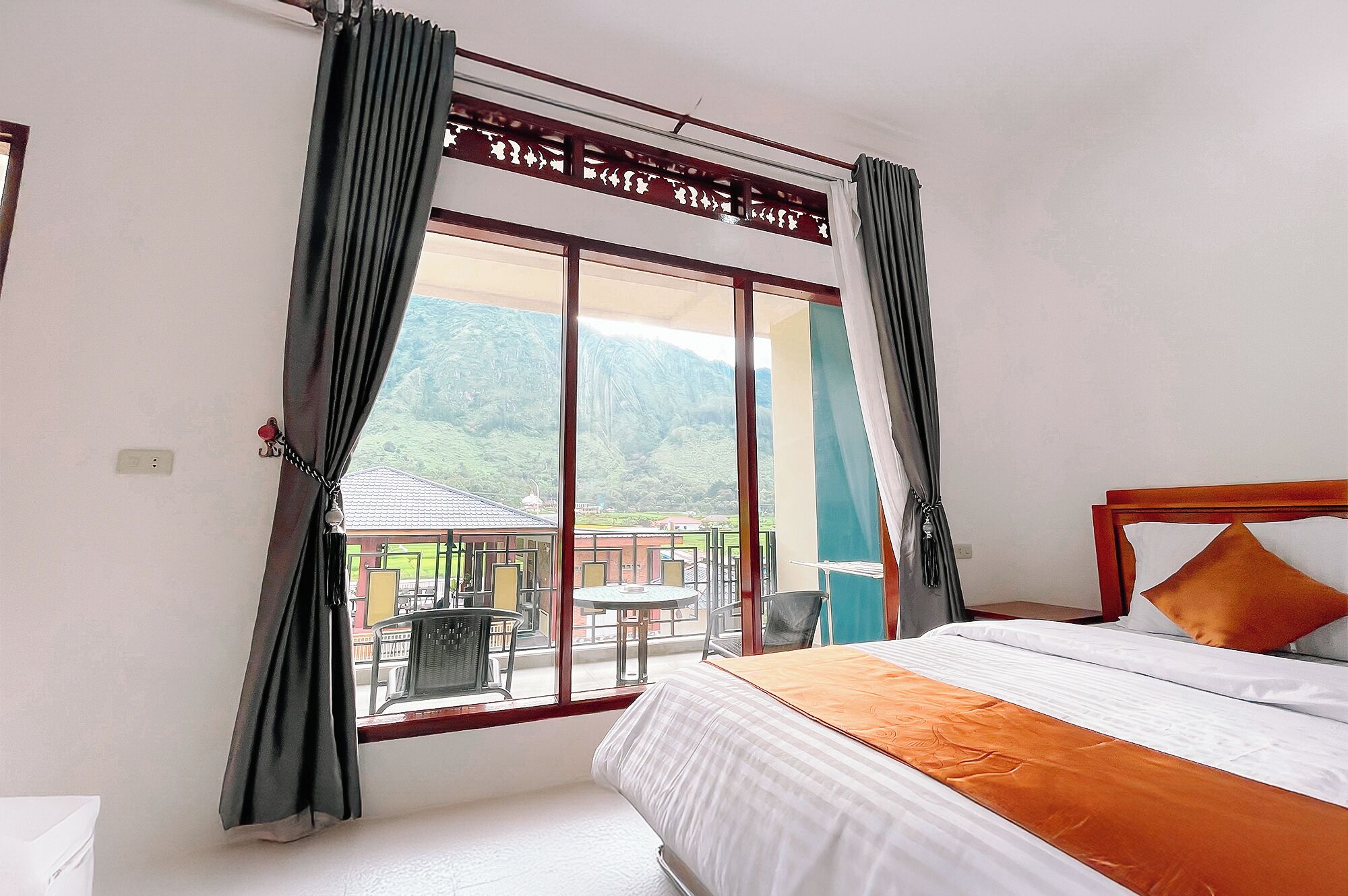 Quarto de hotel com uma grande porta de correr de vidro que dá para uma varanda com vista para a montanha.