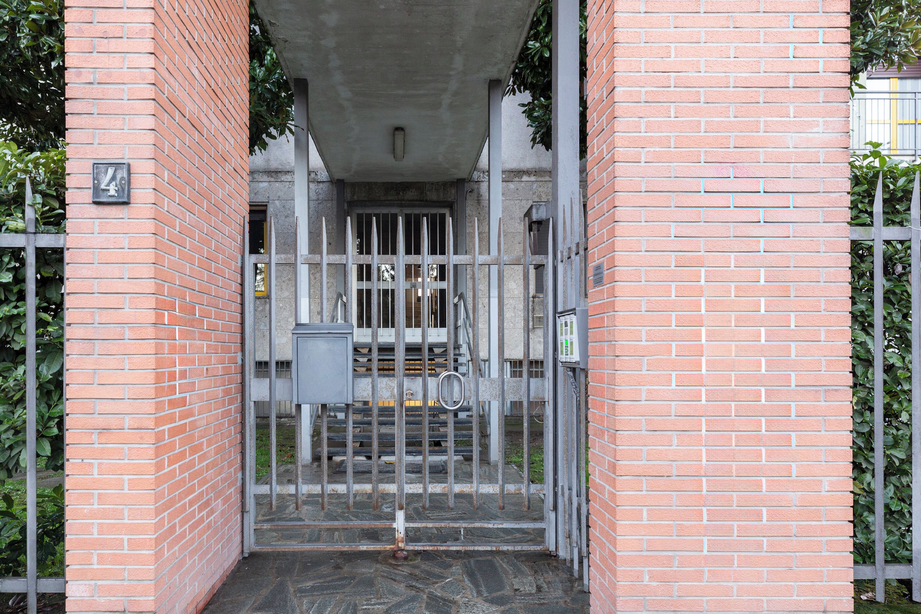 Uma entrada com portão metálico e uma cobertura de concreto.
