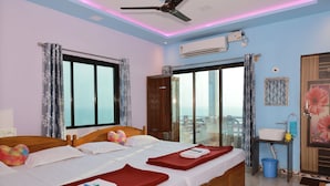 Quarto de hotel com duas camas, varanda e vista, ventoinha no teto e ar condicionado.