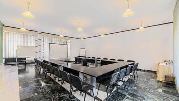 Uma sala de conferência com uma mesa comprida, cadeiras e um quadro branco.