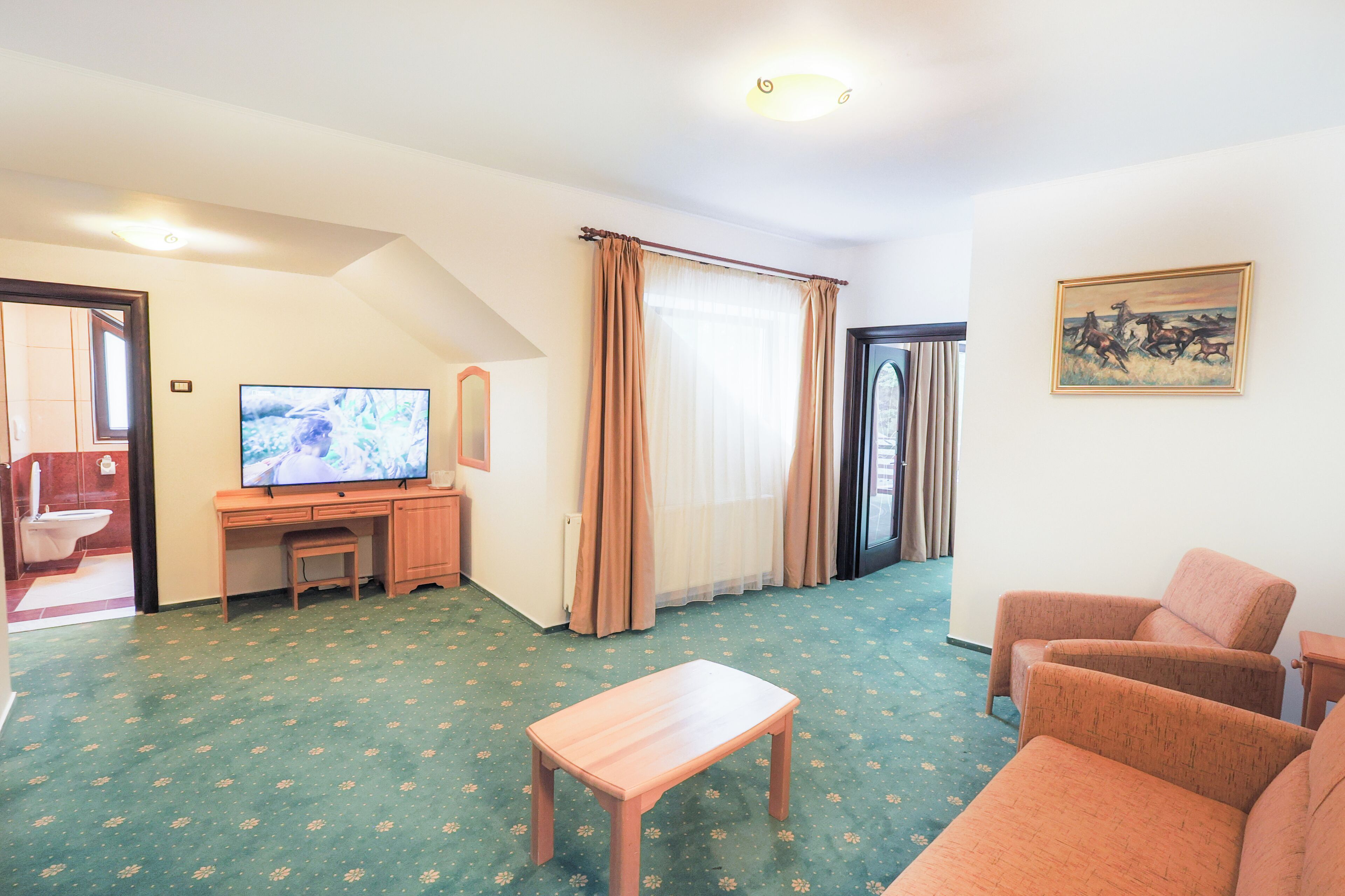 Uma sala de estar com televisão, uma mesa de madeira e dois sofás.