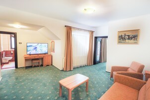 Uma sala de estar com televisão, uma mesa de madeira e dois sofás.