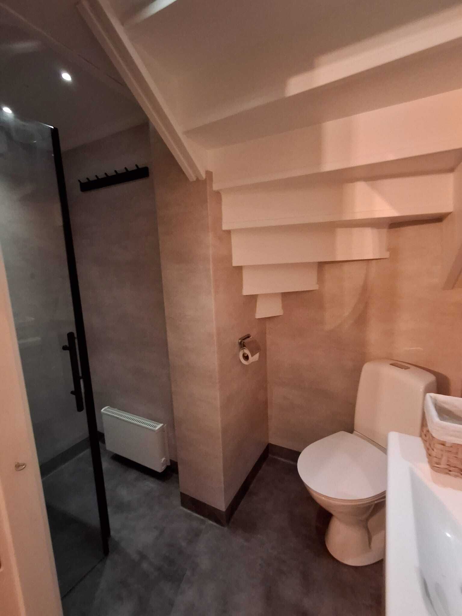 Casa de banho moderna com sanita, chuveiro e porta-toalhas.