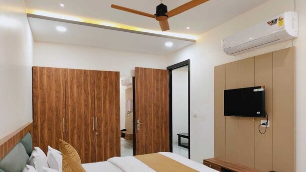 Quarto de hotel com cama, guarda-roupa de madeira, televisão e ar condicionado.