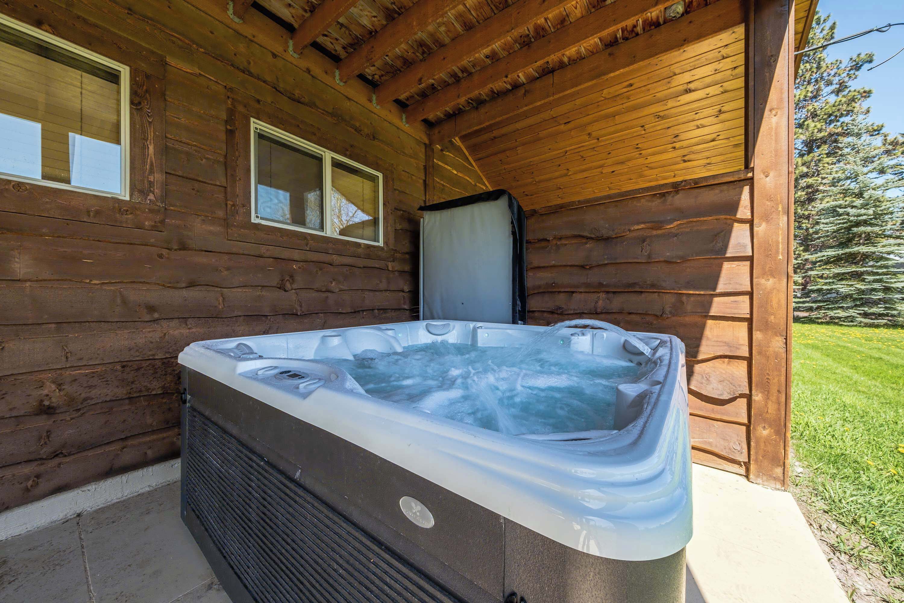Uma cabana de madeira com uma banheira de hidromassagem no exterior.