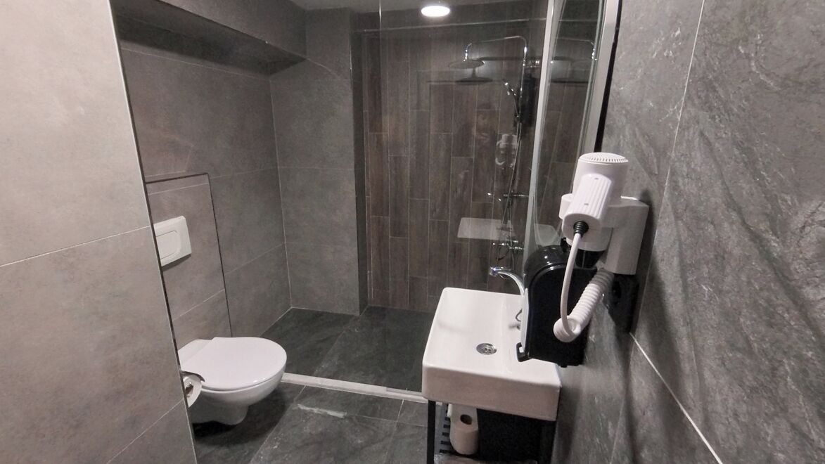 Uma casa de banho moderna com sanita, lavatório e chuveiro.