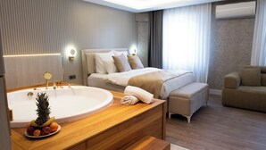 Quarto de hotel moderno com uma cama grande, uma toucador de madeira com pia e uma pequena área de estar.