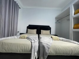 Uma cama de casal com cabeceira preta, duas almofadas e um cobertor.