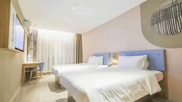 Quarto de hotel com duas camas, uma escrivaninha e uma televisão.