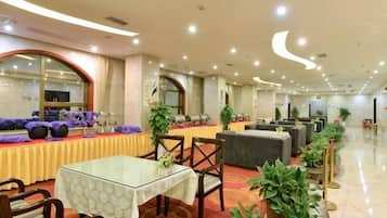 Um saguão de hotel com balcão de recepção, área de estar e mesa de buffet.