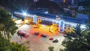 Hotel com estacionamento, vários andares e fachada bem iluminada.
