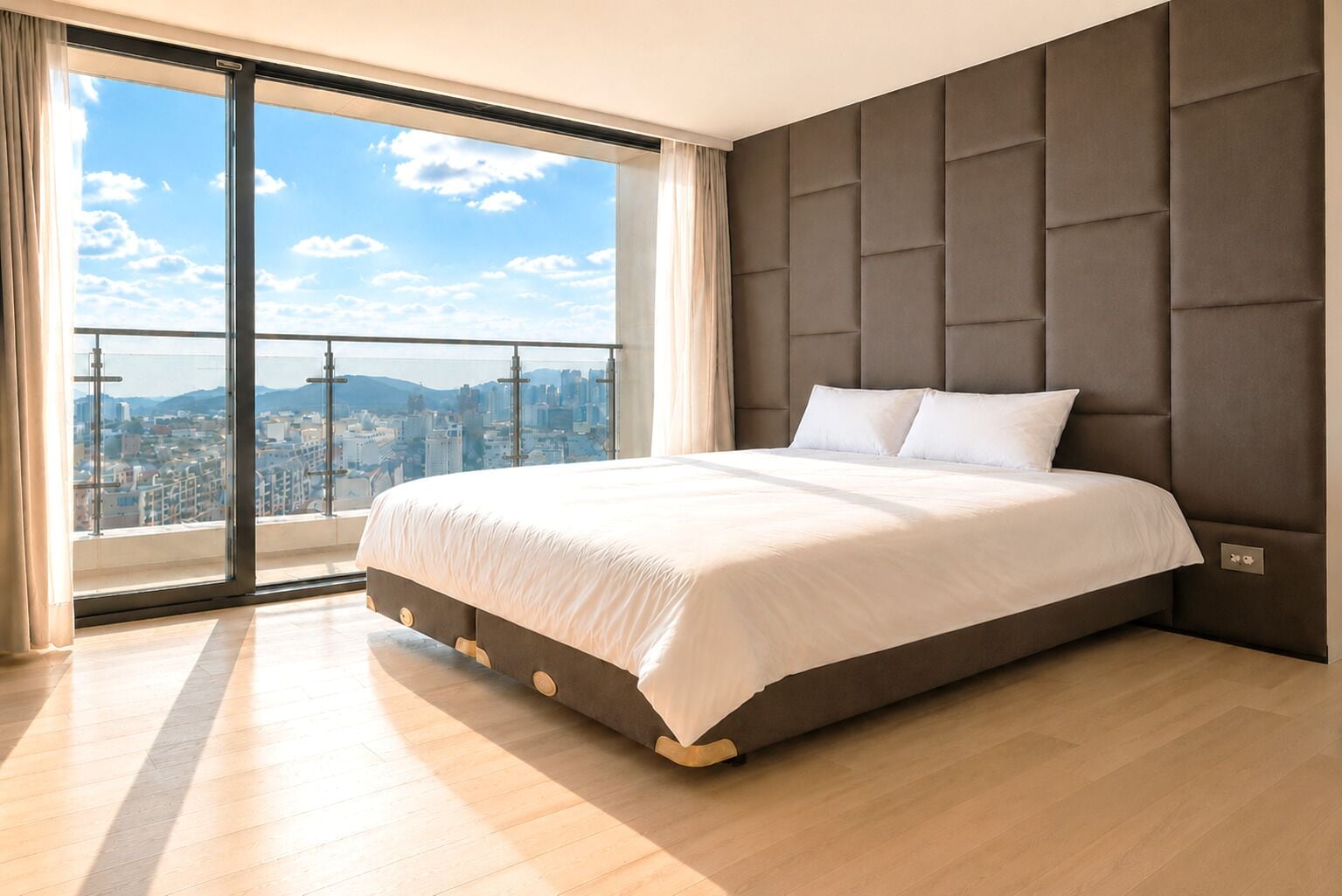 Quarto moderno com uma cama grande, vista para a cidade através de janelas do chão ao teto e piso de madeira.