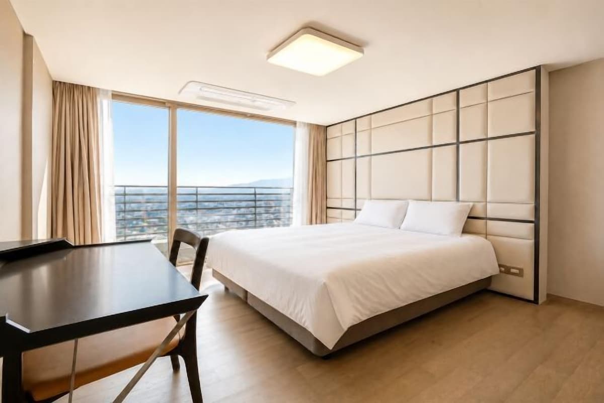 Quarto de hotel com cama, escrivaninha e vista da cidade.