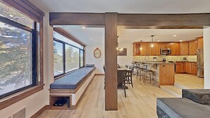 Uma cozinha moderna com armários de madeira, forno embutido e uma grande janela com vista para uma paisagem nevada.