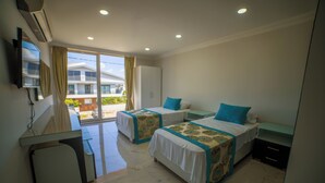 Quarto de hotel com duas camas, uma mesa de trabalho e vista para um edifício.