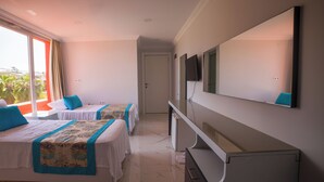 Quarto de hotel com duas camas, televisão e uma janela grande.