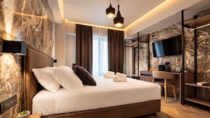 Quarto de hotel moderno com uma cama grande, uma escrivaninha, televisão de tela plana e parede de mármore.