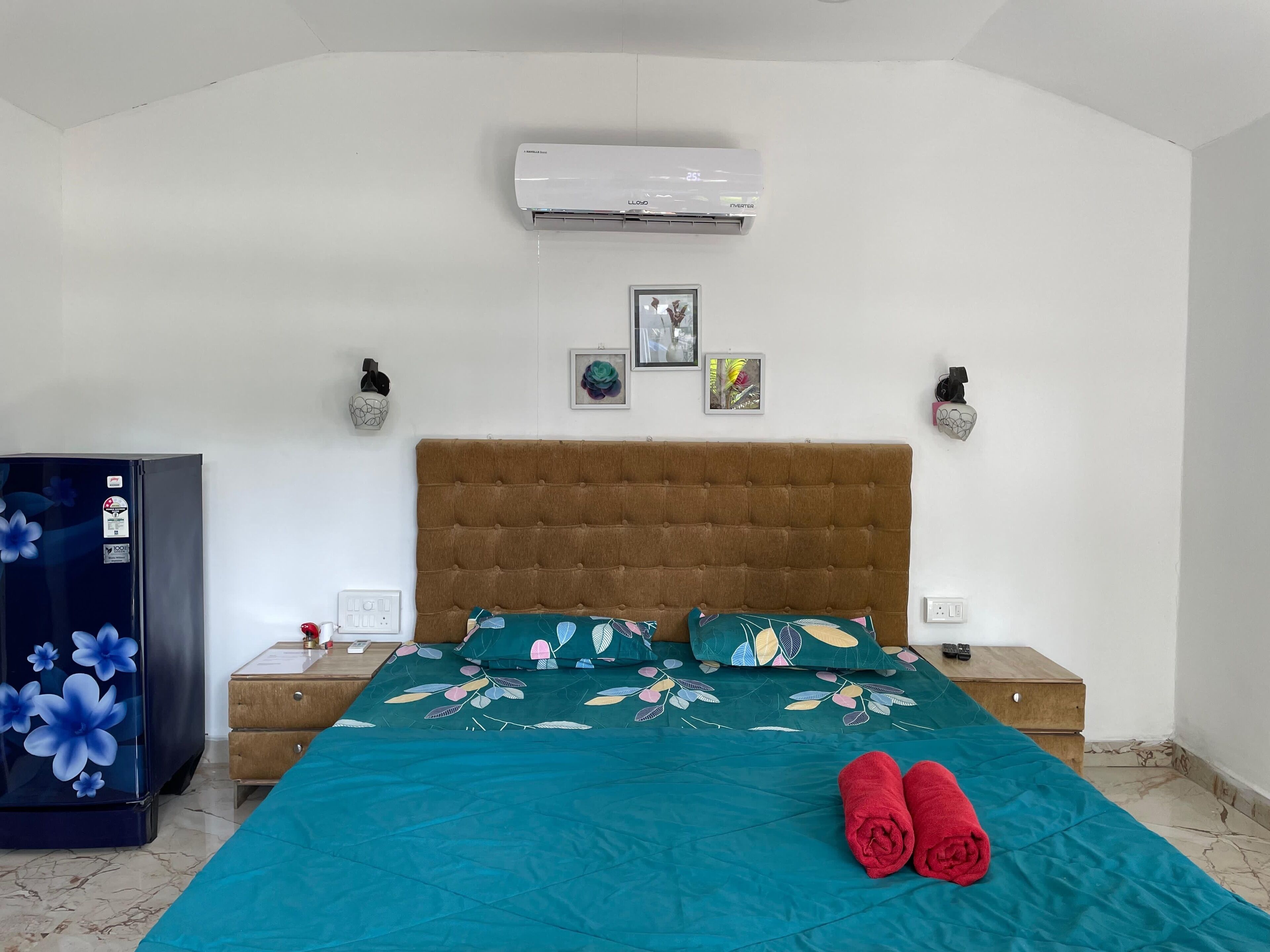 Quarto com cama, mesa de cabeceira, cômoda, ar condicionado e geladeira.