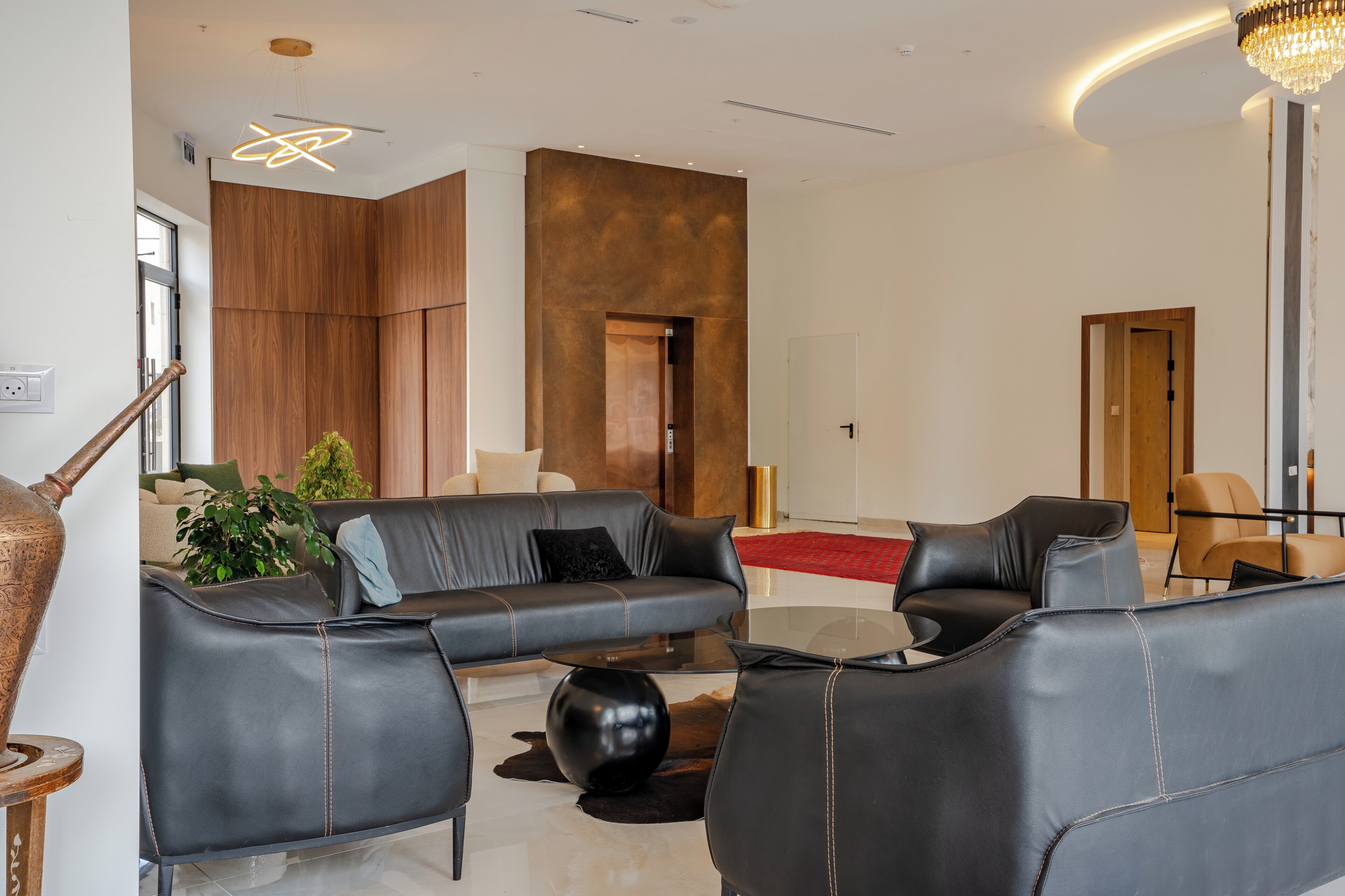 Uma sala de estar moderna com sofás de couro, uma mesa de centro de vidro e uma parede de destaque em madeira.